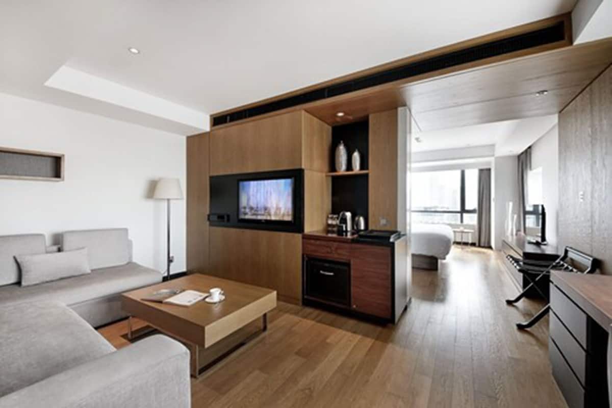 Uma sala de estar moderna com sofá, mesa de centro, televisão e cozinha com armários e mesa de jantar.