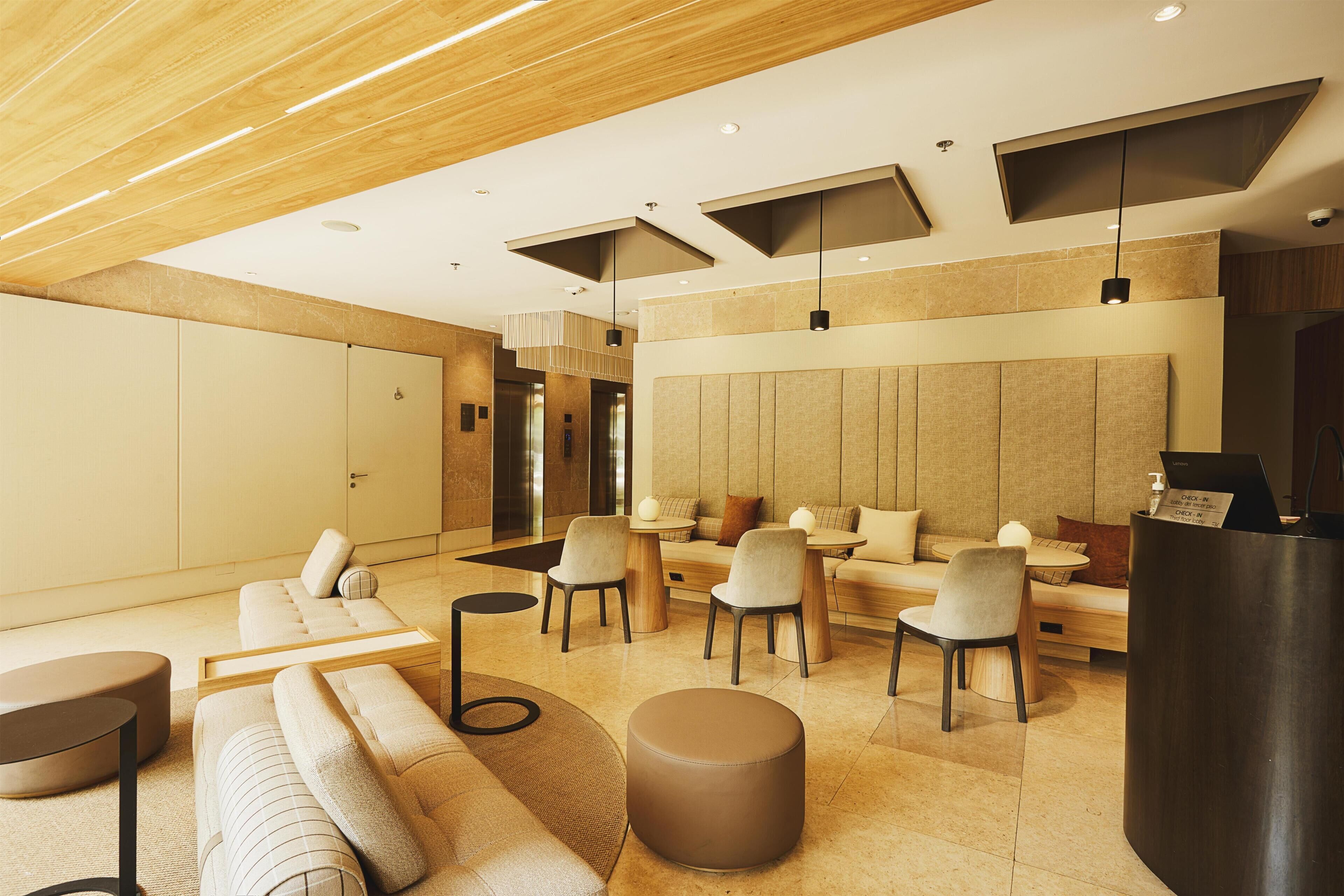 Um lobby moderno com sofás, cadeiras, balcão de recepção e teto de madeira.
