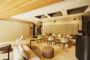 Um lobby moderno com sofás, cadeiras, balcão de recepção e teto de madeira.
