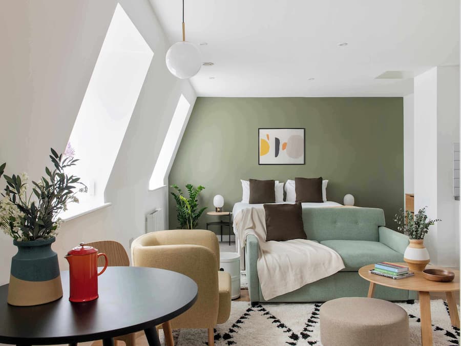 Quarto moderno e bem iluminado, com cama, área de estar e mesa de jantar.