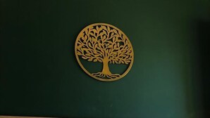 Cama bem arrumada com lençóis brancos e um cobertor branco fofo, cabeceira de madeira e um adorno de árvore fixado na parede.