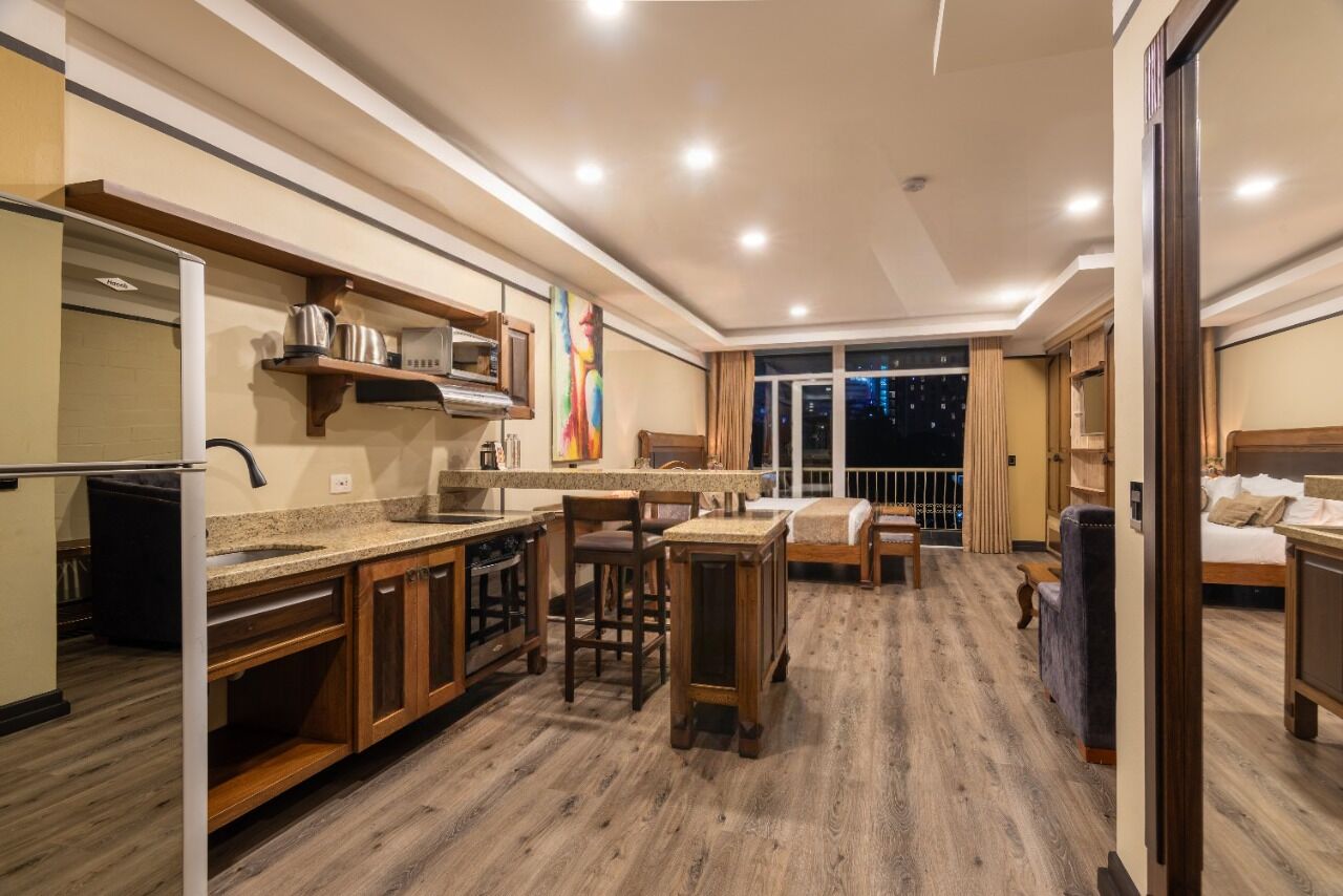 Cozinha moderna com armários de madeira, bancada de granito e área de refeições com mesa e cadeiras.
