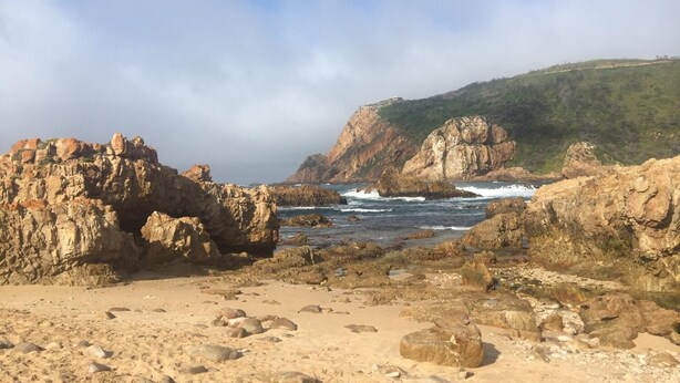 Paisagem costeira rochosa com grandes pedras e falésias.