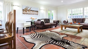 Uma sala de estar com um tapete de zebra, sofás de couro, uma mesa de centro de madeira e um quadro de girafas.