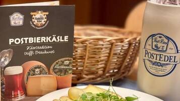 Um prato de panquecas enroladas com a etiqueta 'POSTBIERKÄSLE' e uma garrafa de cerveja 'POSTEDEL'.