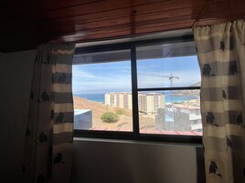 Janela com vista para um horizonte costeiro urbano, incluindo edifícios e uma grua.