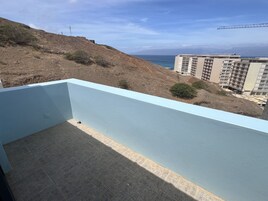 Varanda com vista para uma paisagem montanhosa e um canteiro de obras.