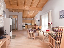 Um espaço de estar moderno com cozinha, sala de jantar e televisão.