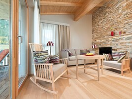 Uma sala de estar moderna com teto de madeira, parede de pedra, sofá, poltrona de balanço e televisão.
