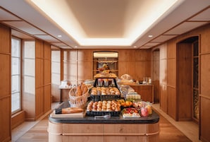 Um buffet de café da manhã com diversos pães e frutas.