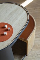 Uma mesa redonda de madeira com borda curva e superfície que imita couro marrom.