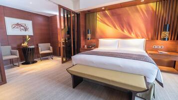Quarto de hotel com uma cama grande, uma mesa de cabeceira, uma cadeira, uma pequena mesa com um vaso e uma parede com um quadro.