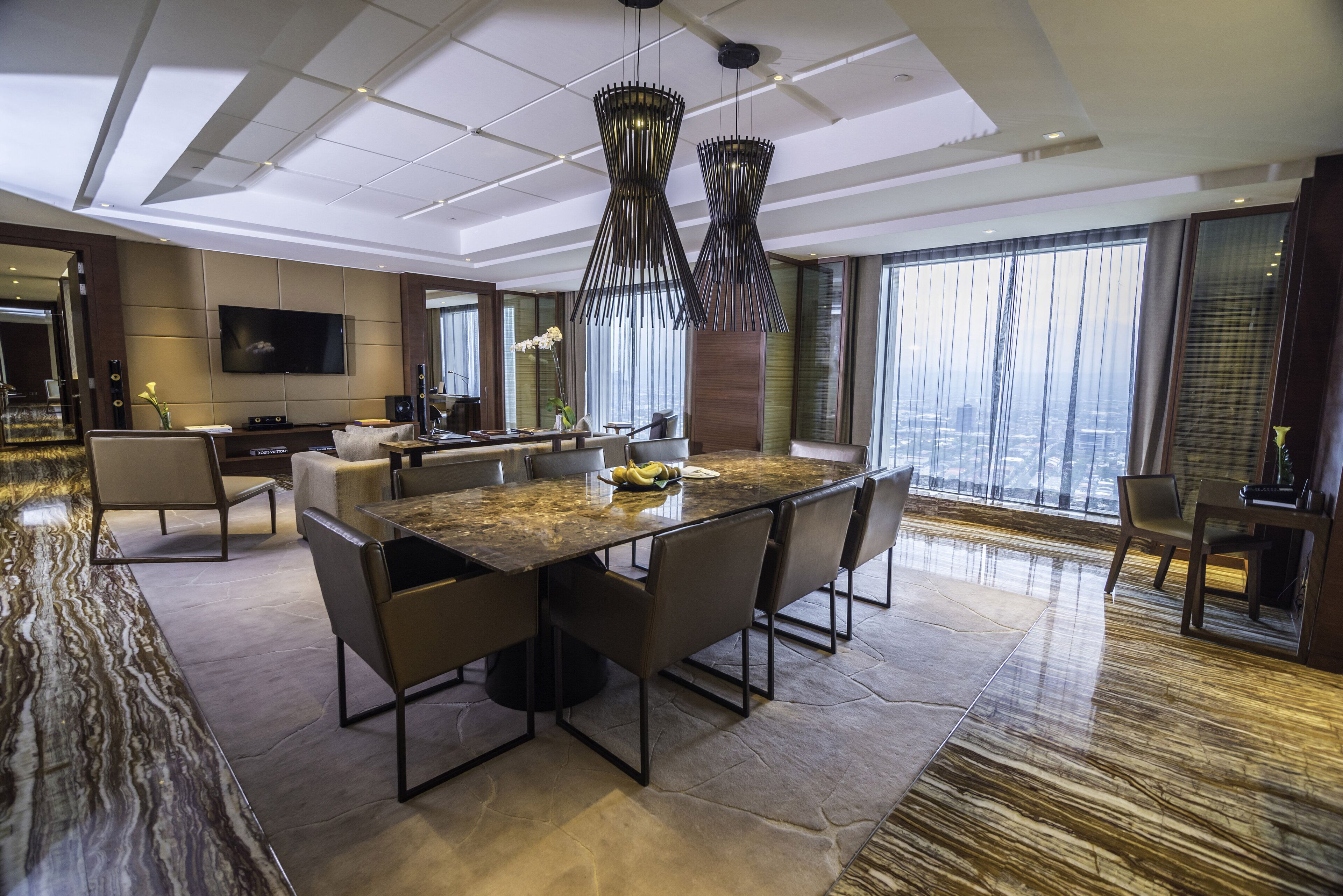 Uma área de refeições moderna com uma mesa de mármore, assentos confortáveis e uma janela ampla com vista para a cidade.
