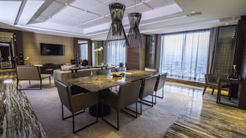 Uma área de refeições moderna com uma mesa de mármore, assentos confortáveis e uma janela ampla com vista para a cidade.