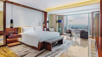 Quarto de hotel moderno com uma cama grande, uma escrivaninha e vista para a cidade.