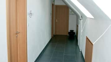 Um corredor com portas de madeira, chão de azulejos pretos e um claraboia.