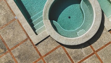 Uma piscina circular com borda azulejada, rodeada por uma área com padrão de pedrinhas.