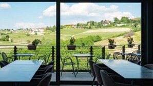 Restaurante com vista para uma paisagem verde e casas.