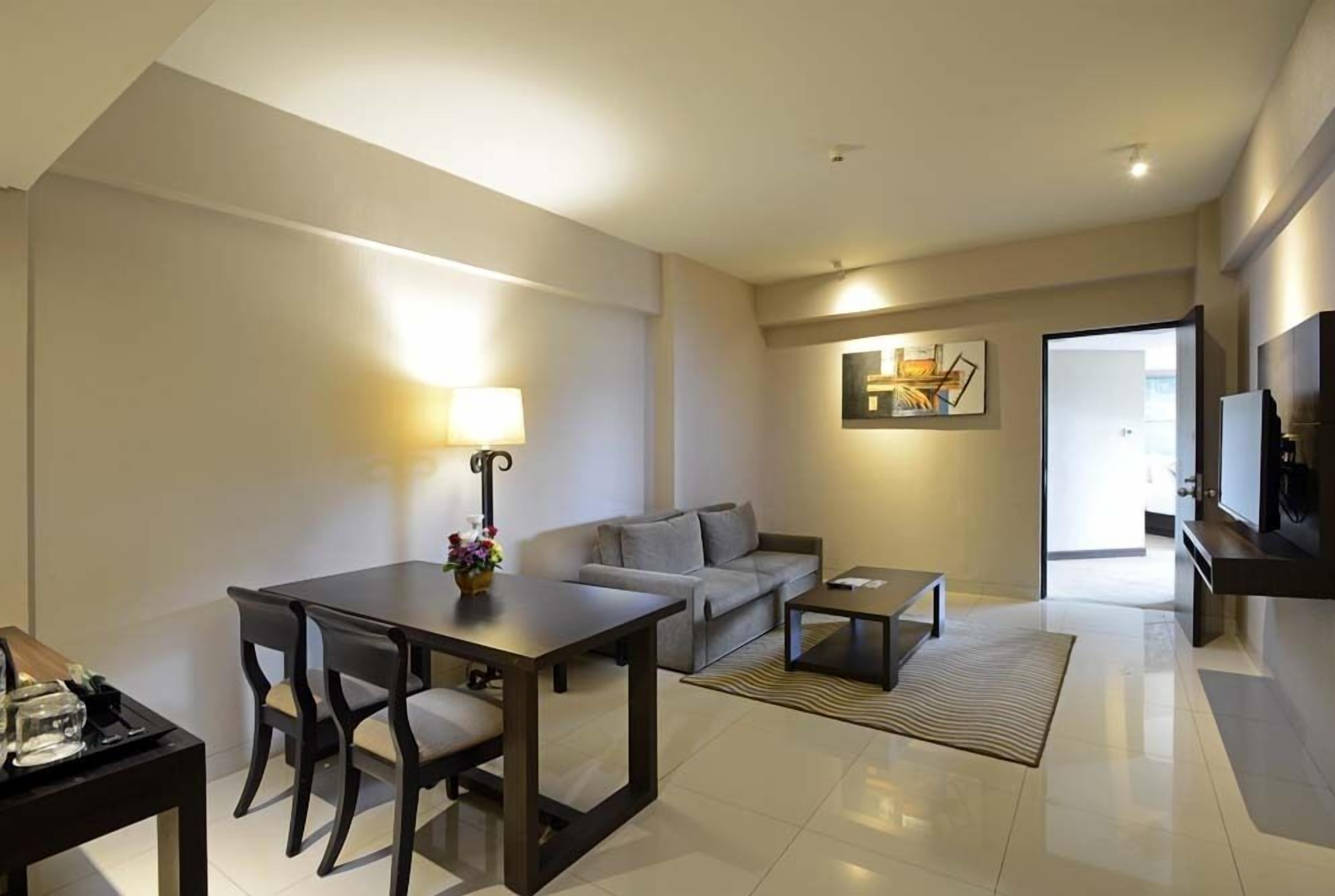 Uma sala de estar moderna com área de jantar, um sofá, uma mesa de centro e uma televisão.