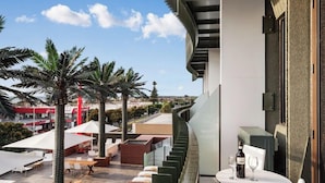 Terraço no telhado com área de estar ao ar livre, palmeiras e vista da cidade.