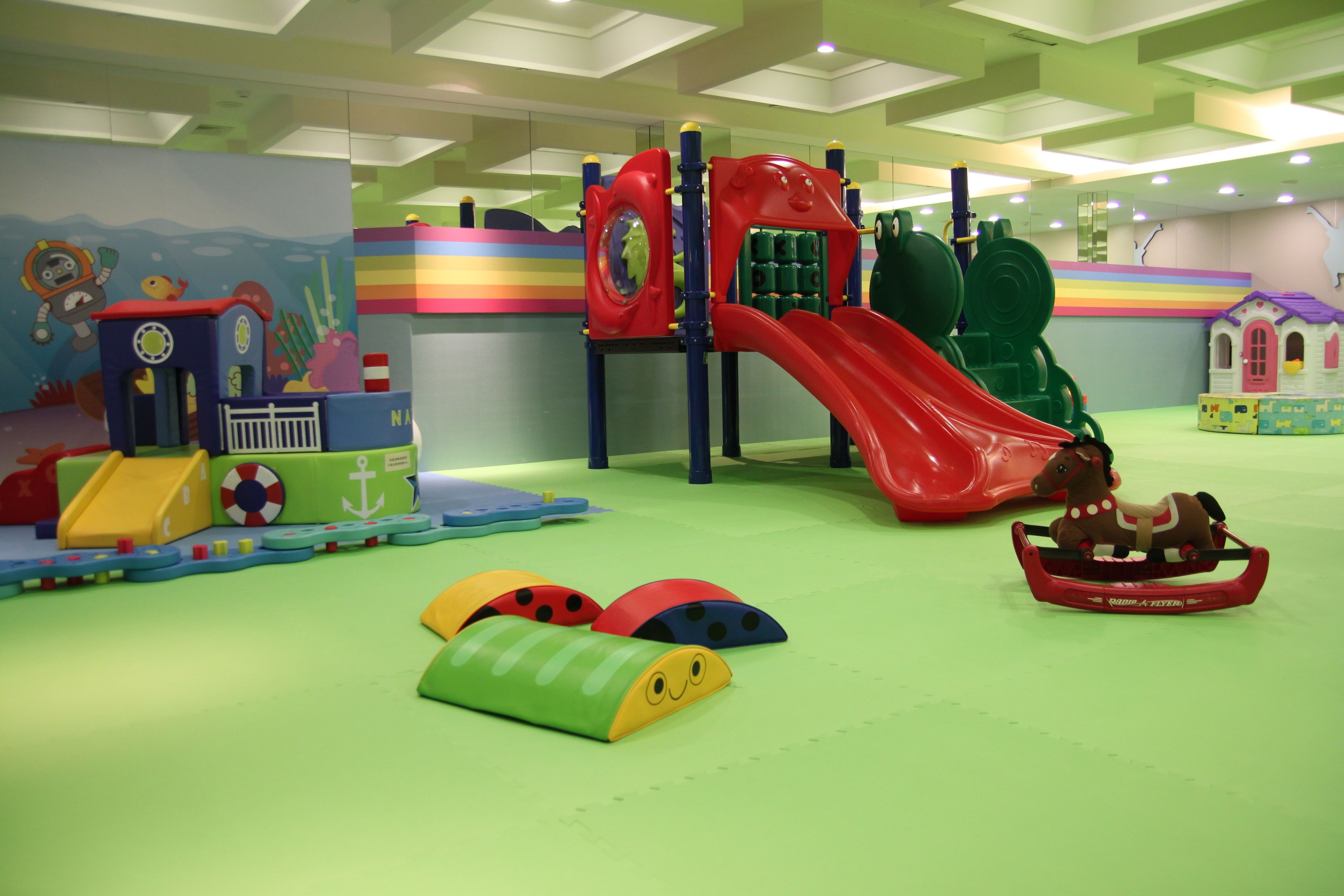 Espaço infantil com escorrega, estruturas de escalada e um passeio de barquinho.