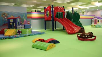 Espaço infantil com escorrega, estruturas de escalada e um passeio de barquinho.