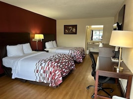 Quarto de hotel com duas camas, uma escrivaninha, uma cadeira, um abajur e um quadro na parede.