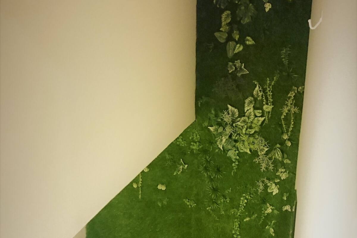 Um quarto pequeno e acolhedor com parede verde, um banco de madeira e uma mesa pequena.