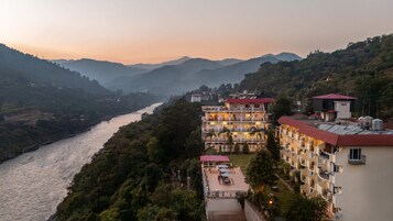 Um hotel com vários andares, varandas e vista para o rio.