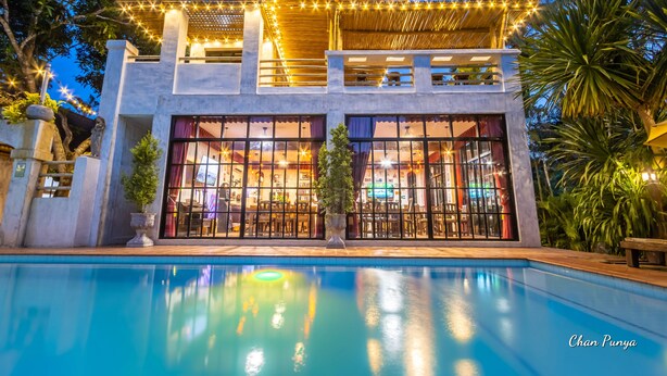 Hotel moderno com piscina, janelas amplas e iluminação externa.