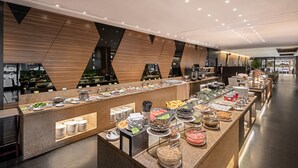 Uma área de buffet com diversos pontos de comida, design de interiores moderno e um balcão extenso.