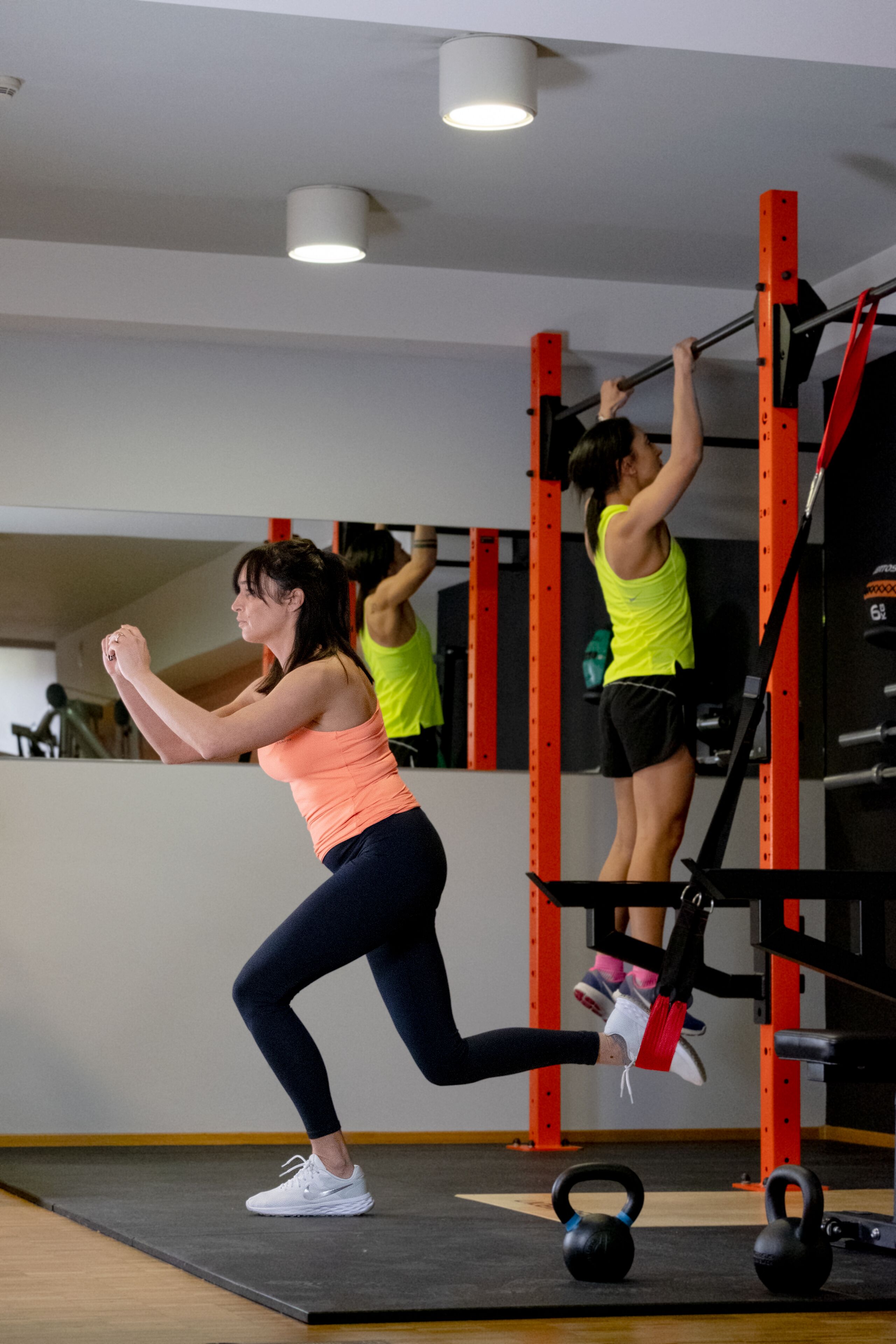 Uma academia com equipamentos de ginástica, incluindo barra de puxar e kettlebells.