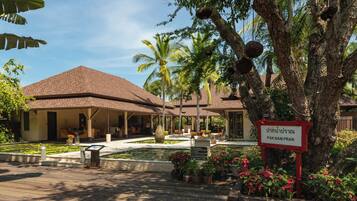 Um resort com um alpendre coberto, palmeiras e uma placa com a inscrição 'Pak Nam Pran'.