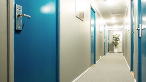 Um corredor com portas azuis, um interruptor de luz e um vaso de plantas.