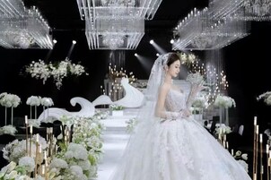 Espaço para casamento com corredor branco, decoração floral e lustres pendurados.