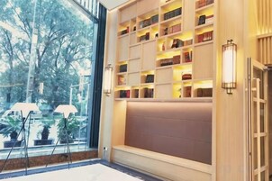 Um quarto com uma janela ampla, uma estante de livros e um espaço para sentar.