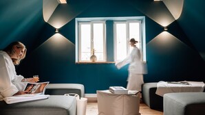 Quarto moderno com uma janela grande, dois sofás, uma mesinha e um candeeiro de chão.