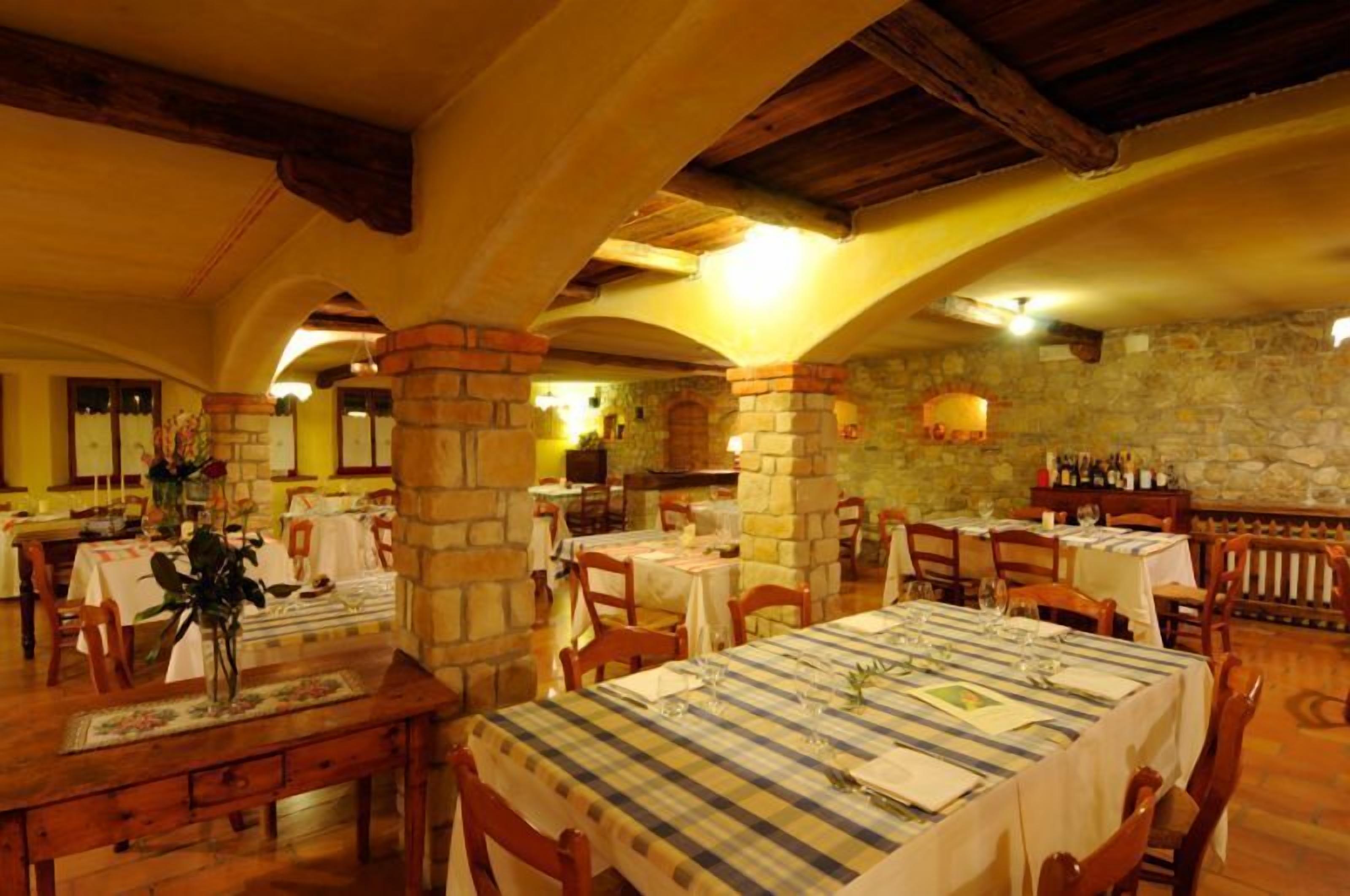 Um restaurante com paredes de pedra, vigas de madeira e mesas preparadas para refeições.