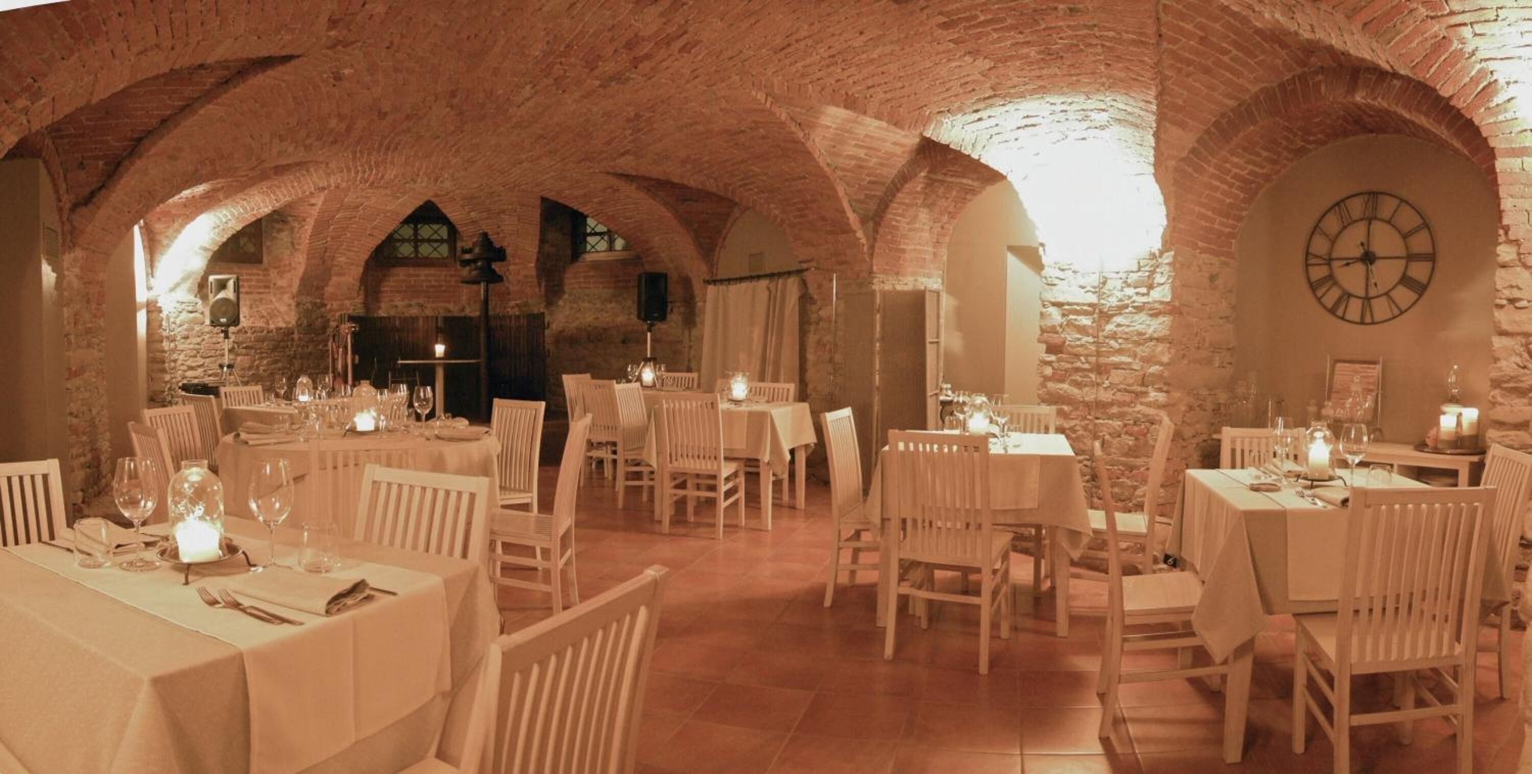 Restaurante com arcos de tijolo, mesas brancas e iluminação de velas.