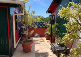 Pátio com plantas em vasos, piso de azulejos e cerca decorativa.