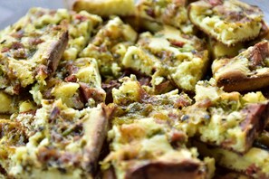 Um close-up de um prato com diversos ingredientes, possivelmente uma torta salgada ou um gratinado.