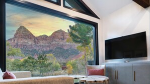Sala de estar moderna com uma grande janela que oferece vista para uma paisagem montanhosa.