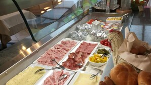 Um buffet com diversos tipos de carne, queijos e pães.