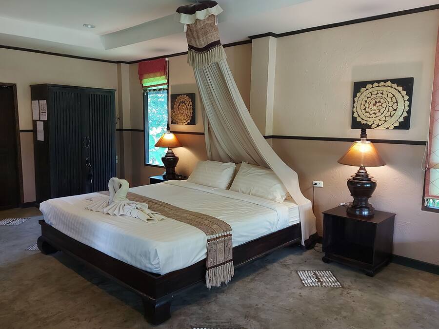 Quarto bem arrumado com cama de dossel, duas luminárias de cabeceira e um detalhe decorativo na parede.