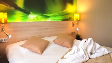 Quarto de hotel com cama, duas almofadas, toalha, mesa de cabeceira, abajur e parede com design verde e amarelo.