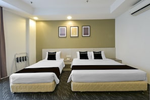 Quarto de hotel com duas camas, cabeceira, telefone fixado na parede e radiador.