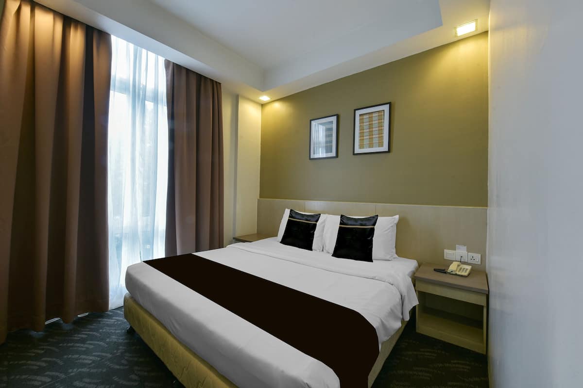 Quarto de hotel com cama, mesa de cabeceira e cortinas.