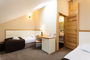 Quarto de hotel com cama, escrivaninha, cadeira, pequena cozinha e guarda-roupa de madeira.