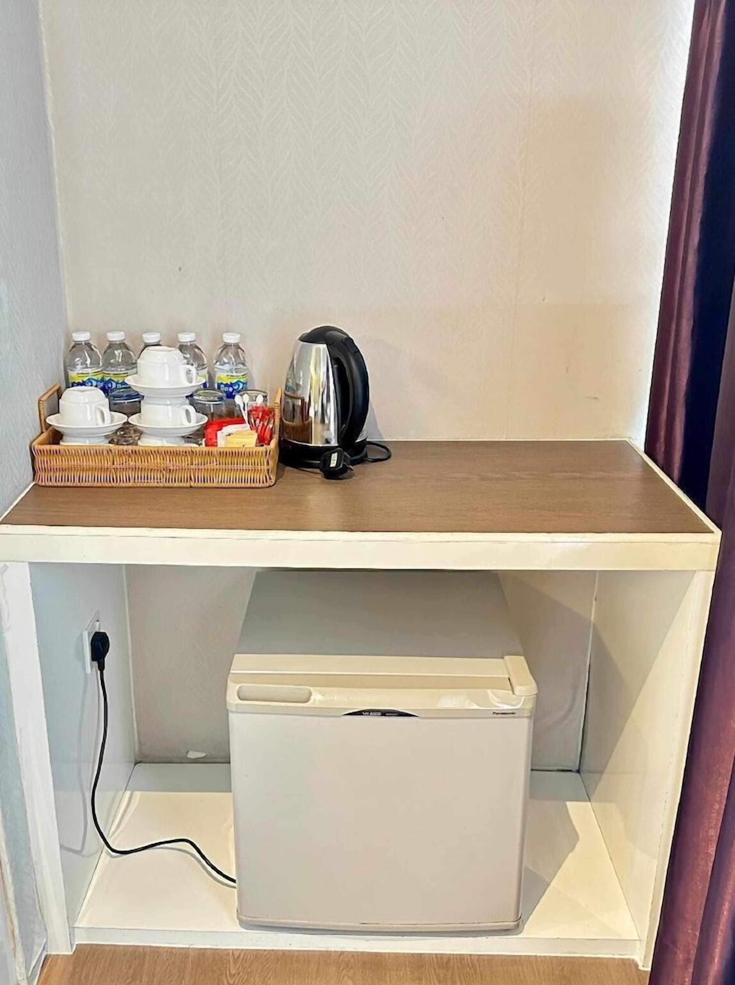 Uma cozinha compacta equipada com cafeteira, chaleira e mini-geladeira.