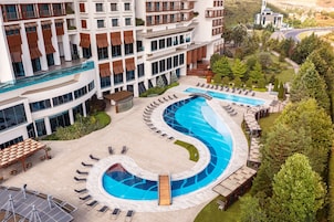 Um hotel moderno com uma grande piscina, áreas de estar ao ar livre e vista para a paisagem circundante.